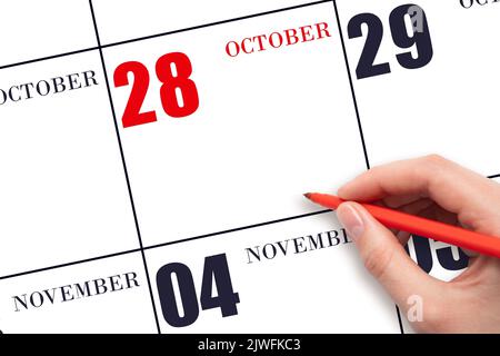 28th day of October. A hand holding a red pen and pointing on the ...