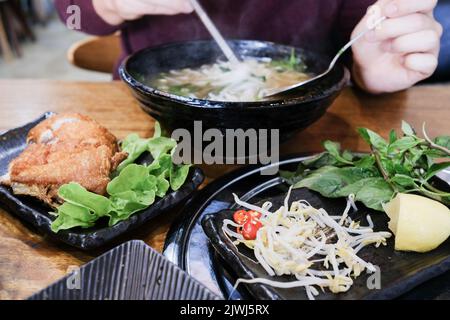 Man eating bowl of Phở Bò (beef pho) and Gà Da Dòn (crispy-skin chicken ...