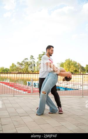 Young attractive couple dancing latin bachata near sea or ocean. Sunlight background. Summer ...