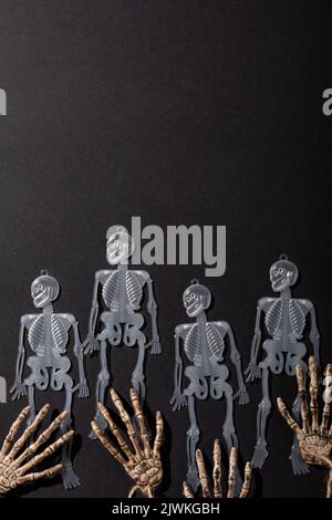 Multiple skeleton toys and skeleton hands with copy space on grey ...