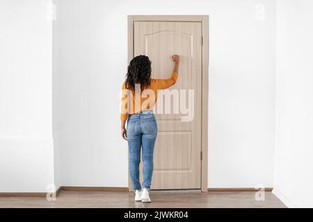 Unrecognizable African American Woman Knocking At Door Indoors, Rear ...