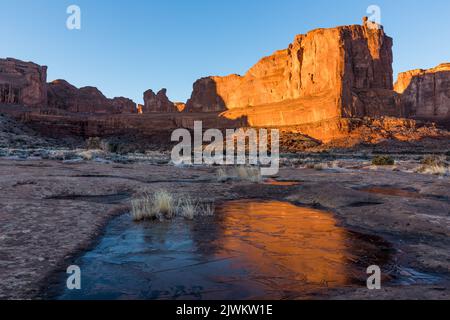 Red sandstone reflected in any icy pothole filled with snowmelt in the ...