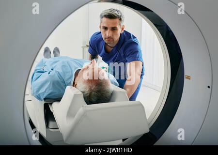 CT scan technologist overlooking patient in Computed Tomography scanner ...