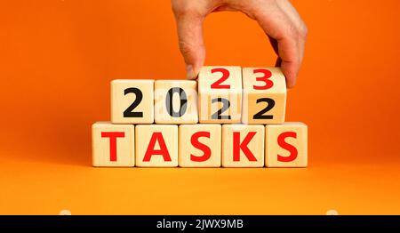 2023 tasks new year symbol. Businessman turns a wooden cube and changes ...