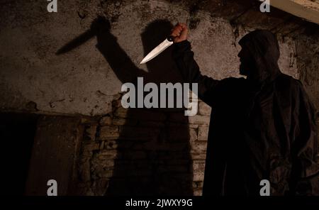 murderer with big knife and shadow horror scene Stock Photo - Alamy