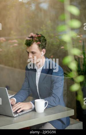 View through glass window of young businesswoman greeting her colleague ...