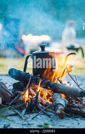Preparing coffee or tea on a bonfire with branches and flames outdoor ...