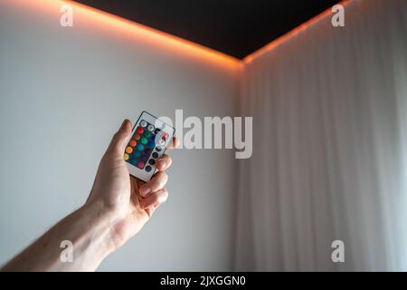 Hand holding led lighting remote control with light turned on ceiling ...