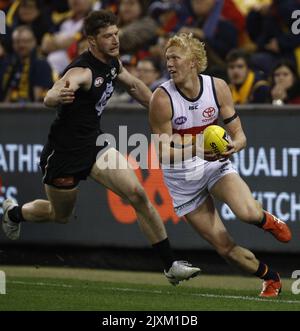 Elliott Himmelberg of the Crows runs with the ball under pressure from ...