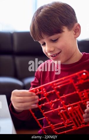 Boy Wearing Pyjamas Building Robotic Arm From Plastic Kit At Home Stock ...