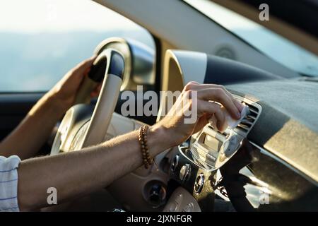 Hand of man with bracelets wipes panel vent with white napkin holding ...