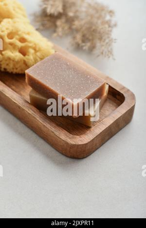Natural soap bars and sponge on wooden tray with various toiletries on ...