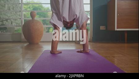Athlete man balances upside down in yoga practice. Person practicing ...