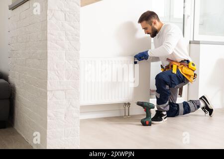 man repairing radiator with wrench. Removing air from the radiator ...