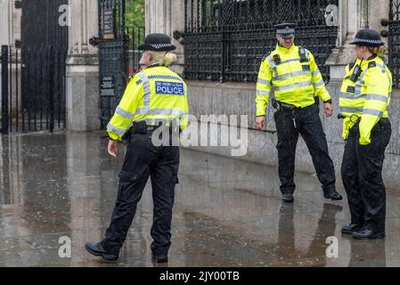 Female police officer getting wet during a heavy rain storm at Trooping ...