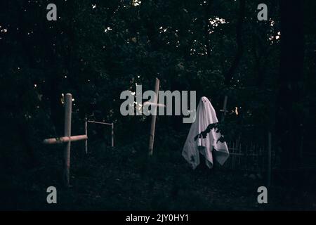 Ghost in the cemetery between graves during Halloween Stock Photo - Alamy