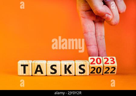 2023 tasks new year symbol. Businessman turns a wooden cube and changes ...
