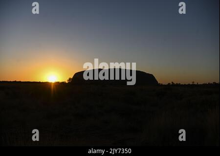 Uluru, also known as Ayers Rock is seen under the Aboriginal flag ...