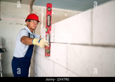 Bricklayer Using a Spirit Level to Check New Red Brick Wall Outdoors ...