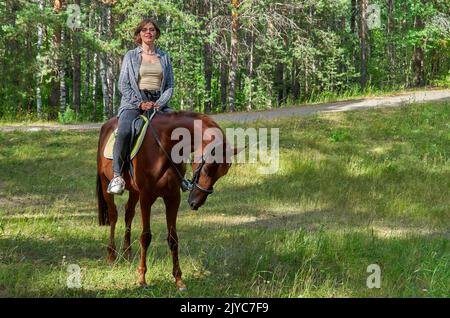 Woman in casual clothes rides a horse in hot summer day Stock Photo - Alamy