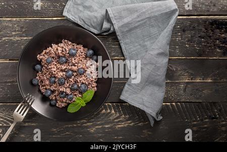 Bowl with delicious rice pudding and blueberries on black background ...