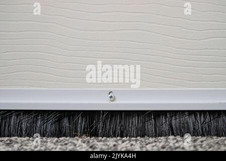 A Man fitting a draught excluder to a door in the UK to reduce heat ...