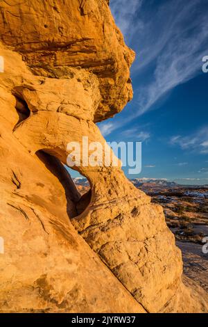A small sandstone mini arch in Arches National Park frames the La Sal ...