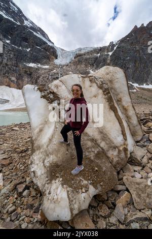 Woman hiker poses with a chunk of glacial ice at Mt. Edith Cavell in ...