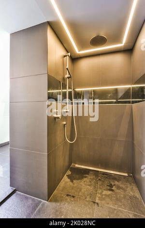 Shower faucets attached to tiled wall near glass partition and ...