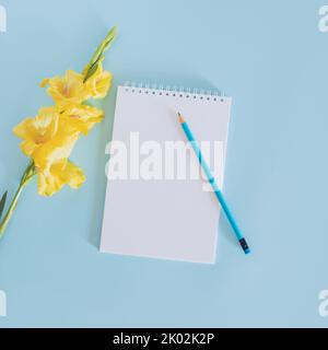 Beautiful yellow Gladiolus flower and a notebook with blank page on a ...