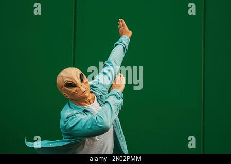 Alien doing dab posture and gesture against a green wall background ...