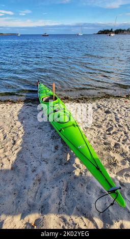 A vertical shot of a canoe on a sandy beach with a background of sea ...