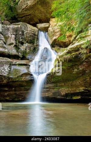 A beautiful shot of a waterfall coming out from a bridge arch in a park ...