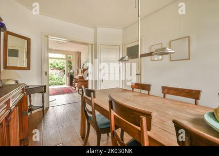 Simple table with chairs located under elegant chandelier near doors in ...