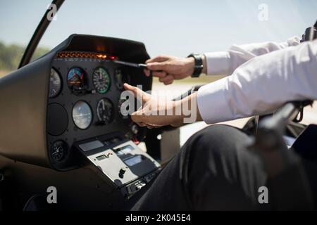 Chinese pilot teaching trainee to operate control panel in cockpit ...