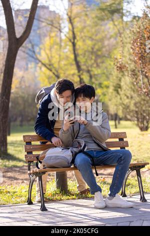 Happy Chinese college students using smart phone on campus Stock Photo ...