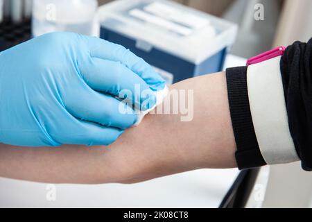 Young Female nurse disinfecting a patient's arm before taking a blood ...