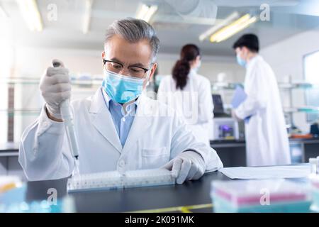 Three Chinese researchers working in laboratory Stock Photo - Alamy