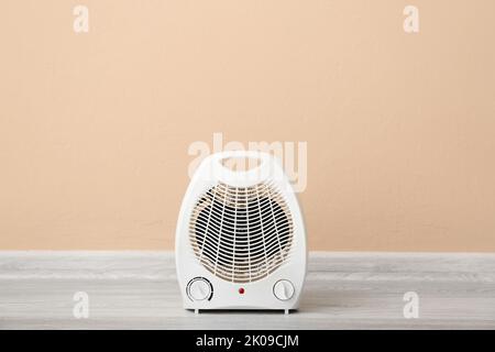 Electric fan heater near beige wall Stock Photo - Alamy