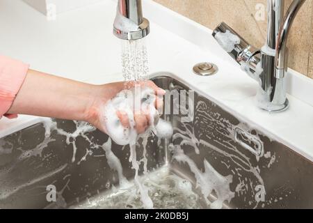 Female hand with sponge and detergent washing glass against blue ...