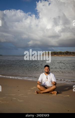 Young hispanic man doing yoga exercise sitting on bench at seaside ...