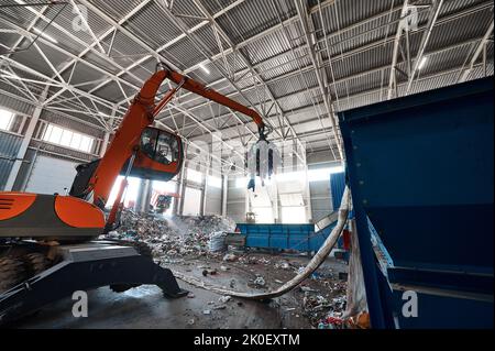Excavator grabs trash in warehouse of waste processing plant Stock ...