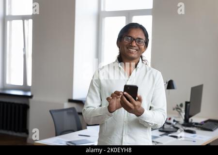 Young indian customer man holding credit card standing over isolated ...