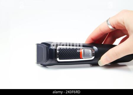 Defocus female hand holding electric clipper on white background ...