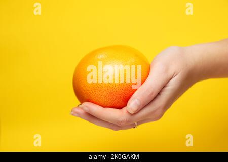 Defocus female hand holding while of a orange fruit. Healthy food ...