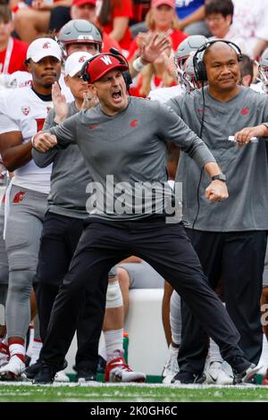 Washington State coach Jake Dickert leads his team onto the field to ...