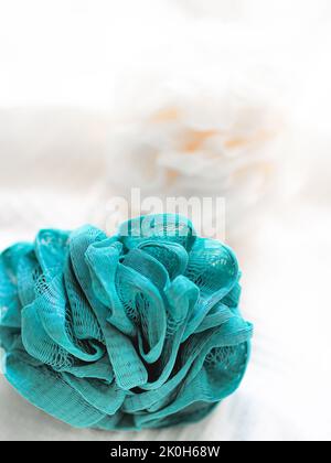 A vertical closeup shot of an aqua colored body sponge on a white cloth ...