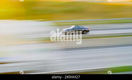 A black car speeding in motion on a highway on a sunny day Stock Photo ...