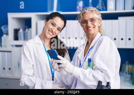 Two women scientists using smartphone and measuring liquid at ...