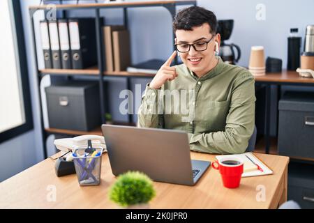 Hispanic male with glasses and earphones pointing with a finger sitting ...